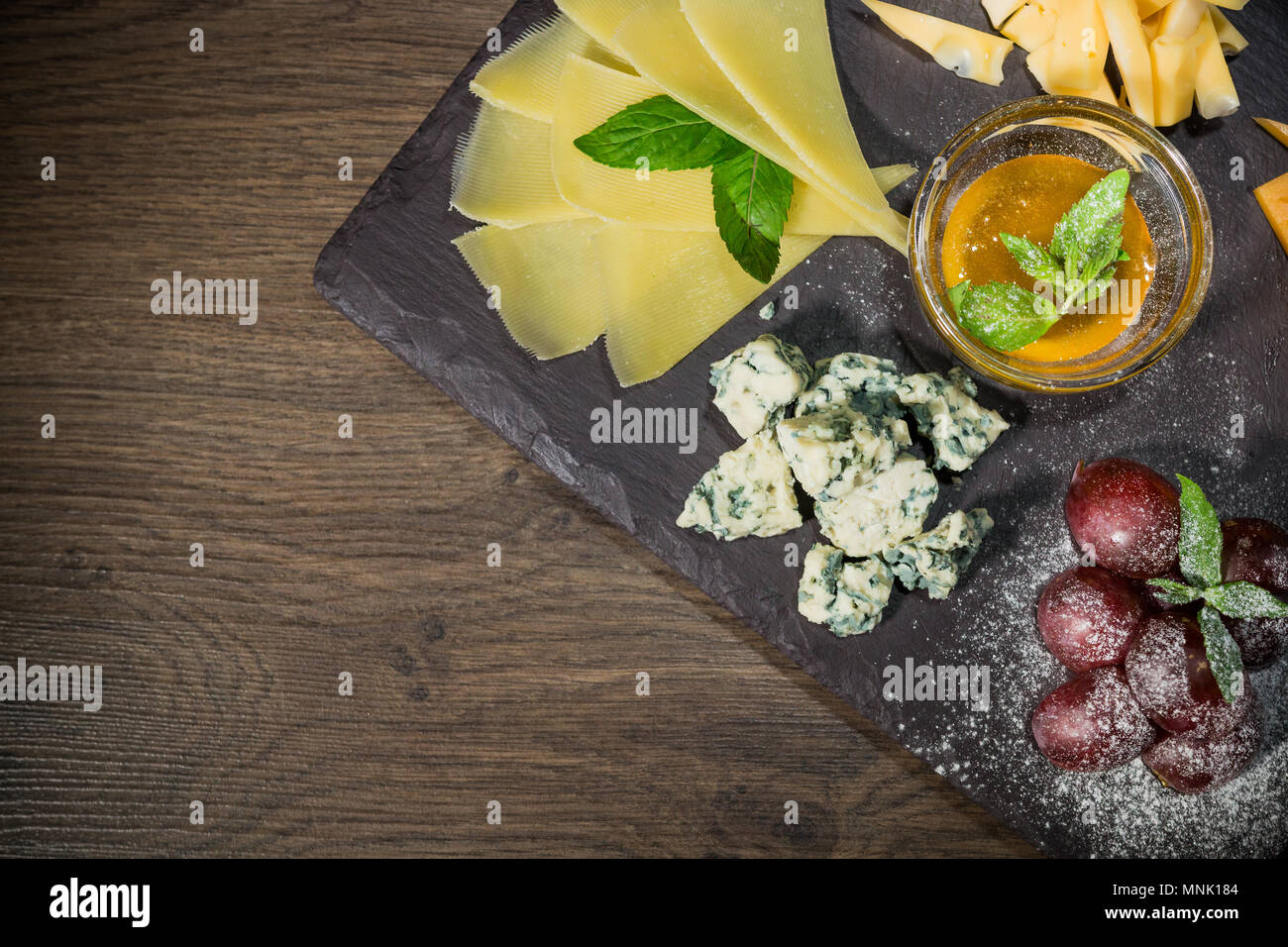 Cheese mix with honey and grapes on a stone background Stock Photo - Alamy