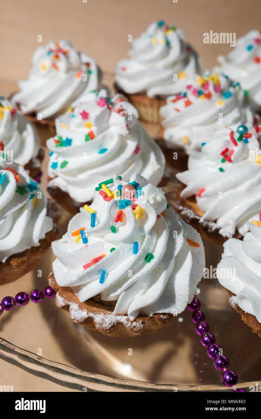 Cakes with white cream and colored powder on a glass stand Stock Photo ...