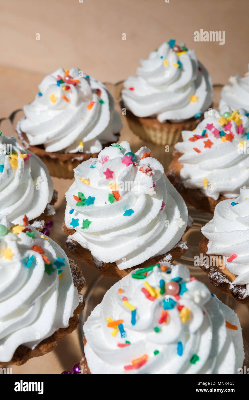 Cakes with white cream and colored powder on a glass stand Stock Photo ...