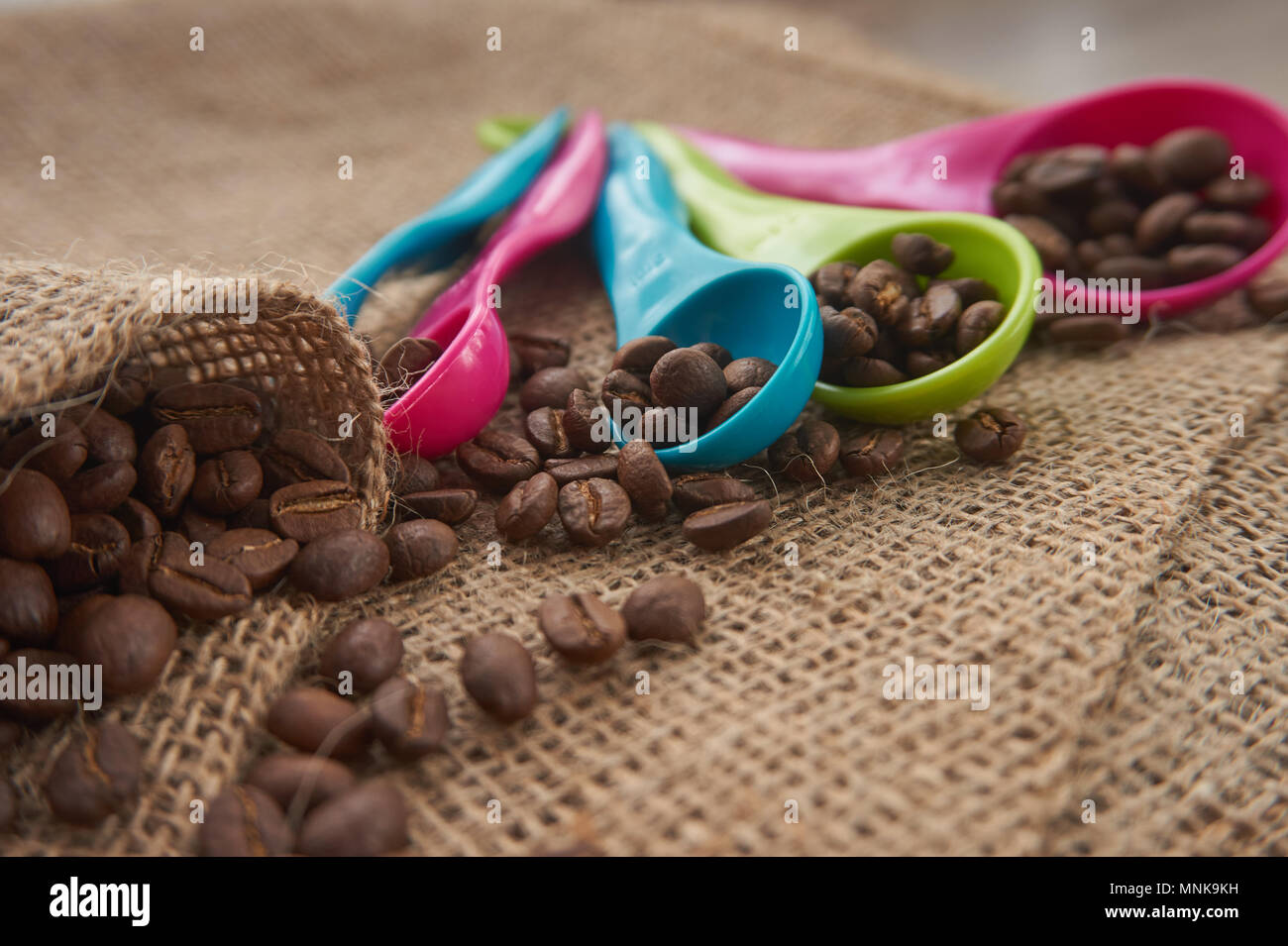 Loose roasted coffee beans and color plastic dose measuring spoons on ...