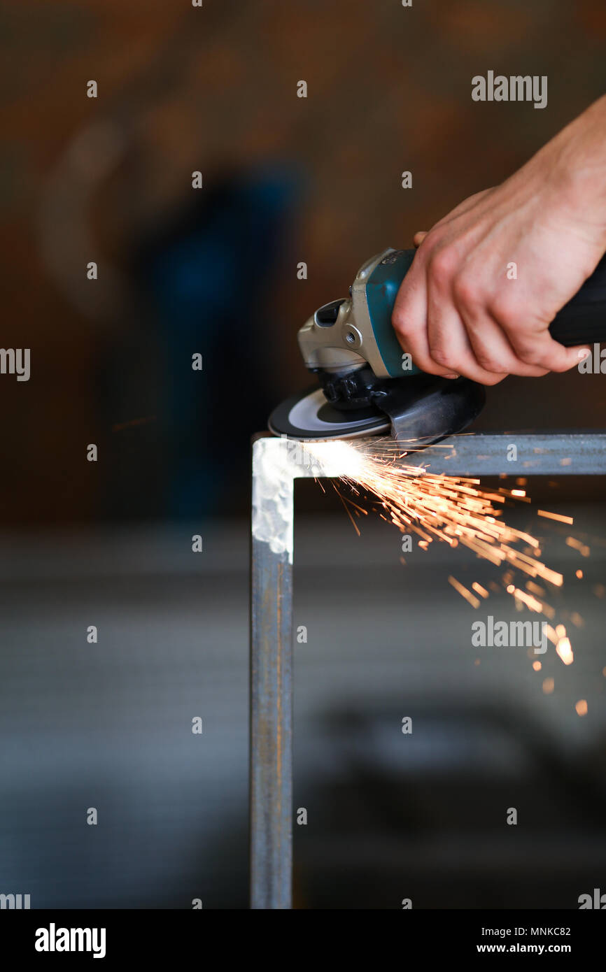 Close up male person sawing metall construction by electrical tool ...