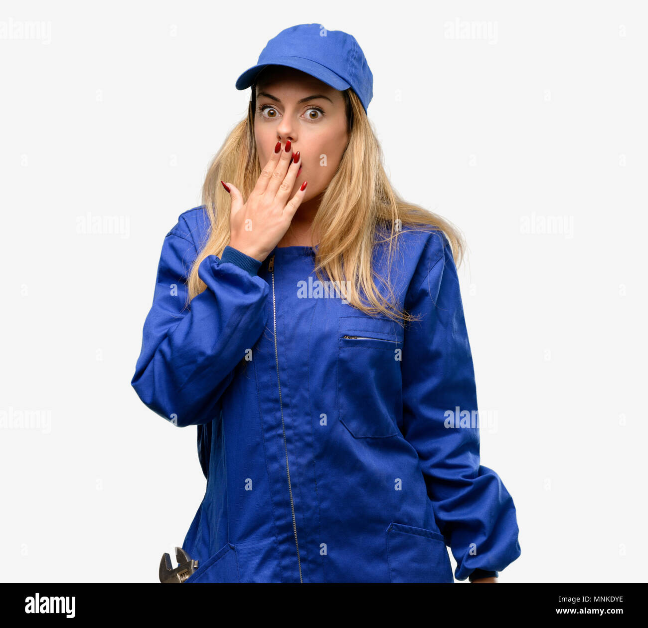 Young plumber woman covers mouth in shock, looks shy, expressing ...