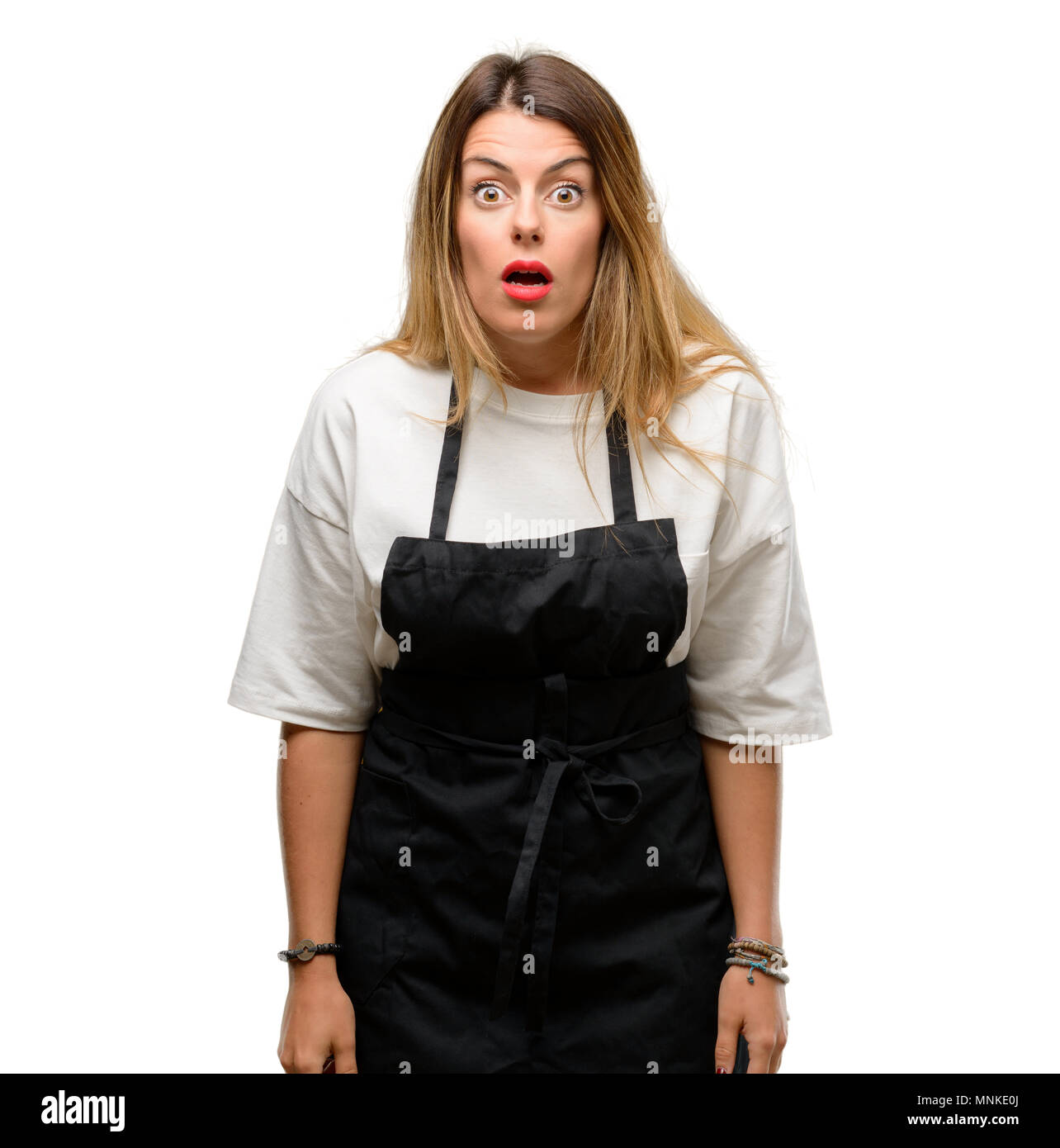 Shop owner woman wearing apron scared in shock, expressing panic and ...
