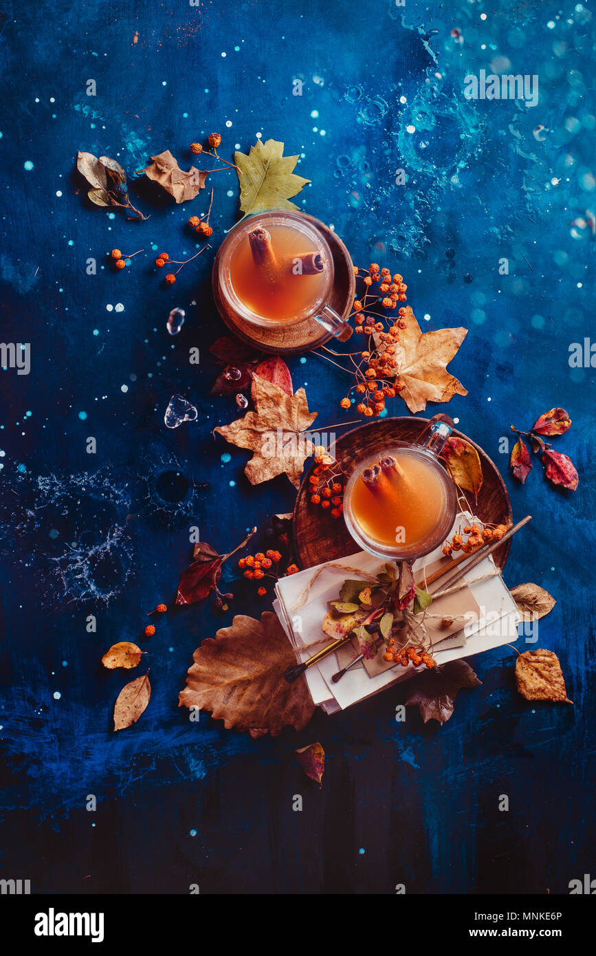 Autumn hot tea with ginger and cinnamon in a glass tea cup on a wet ...