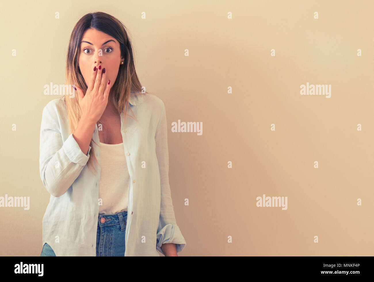 Vintage photo of a Beautiful woman against wall covers mouth in shock ...