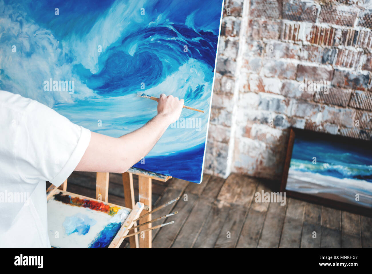 Artist drawing process on canvas in art studio. Painter hold brush in ...