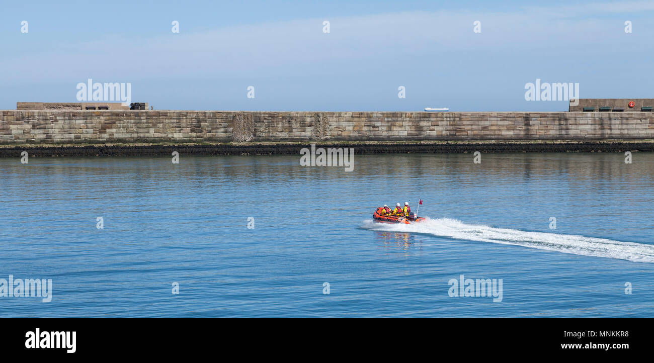 A lifeboat crew leave the harbour in their dinghy at Whitby,North ...