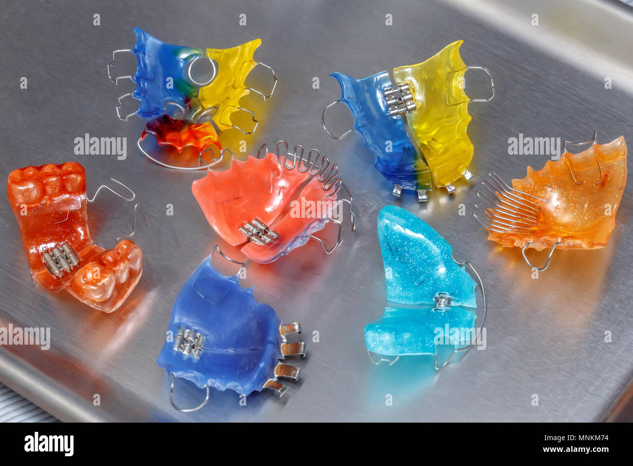 Many colorful dental braces or retainers for teeth on metall background ...