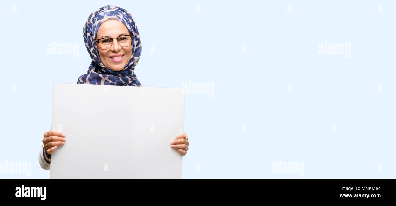 Middle age muslim arab woman wearing hijab holding blank advertising ...