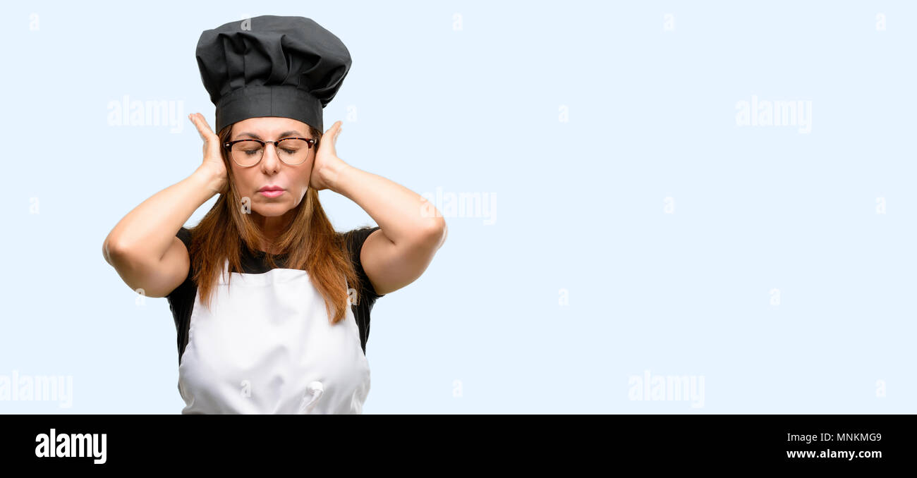Middle age cook woman wearing chef apron covering ears ignoring ...