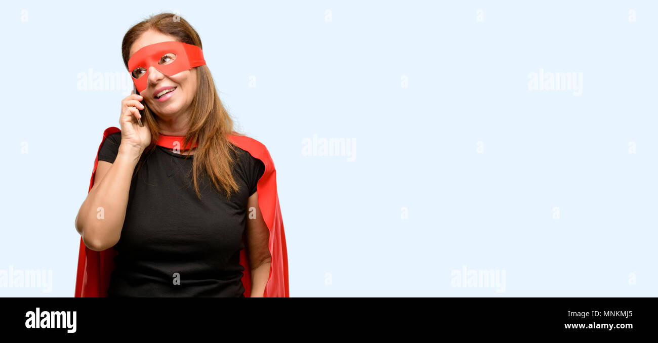 Middle age super hero woman wearing red mask and cape happy talking ...