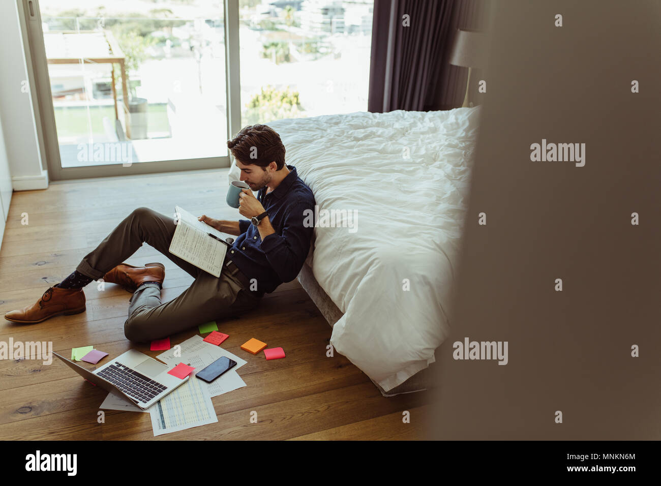 businessman reading his diary while working on laptop computer and ...