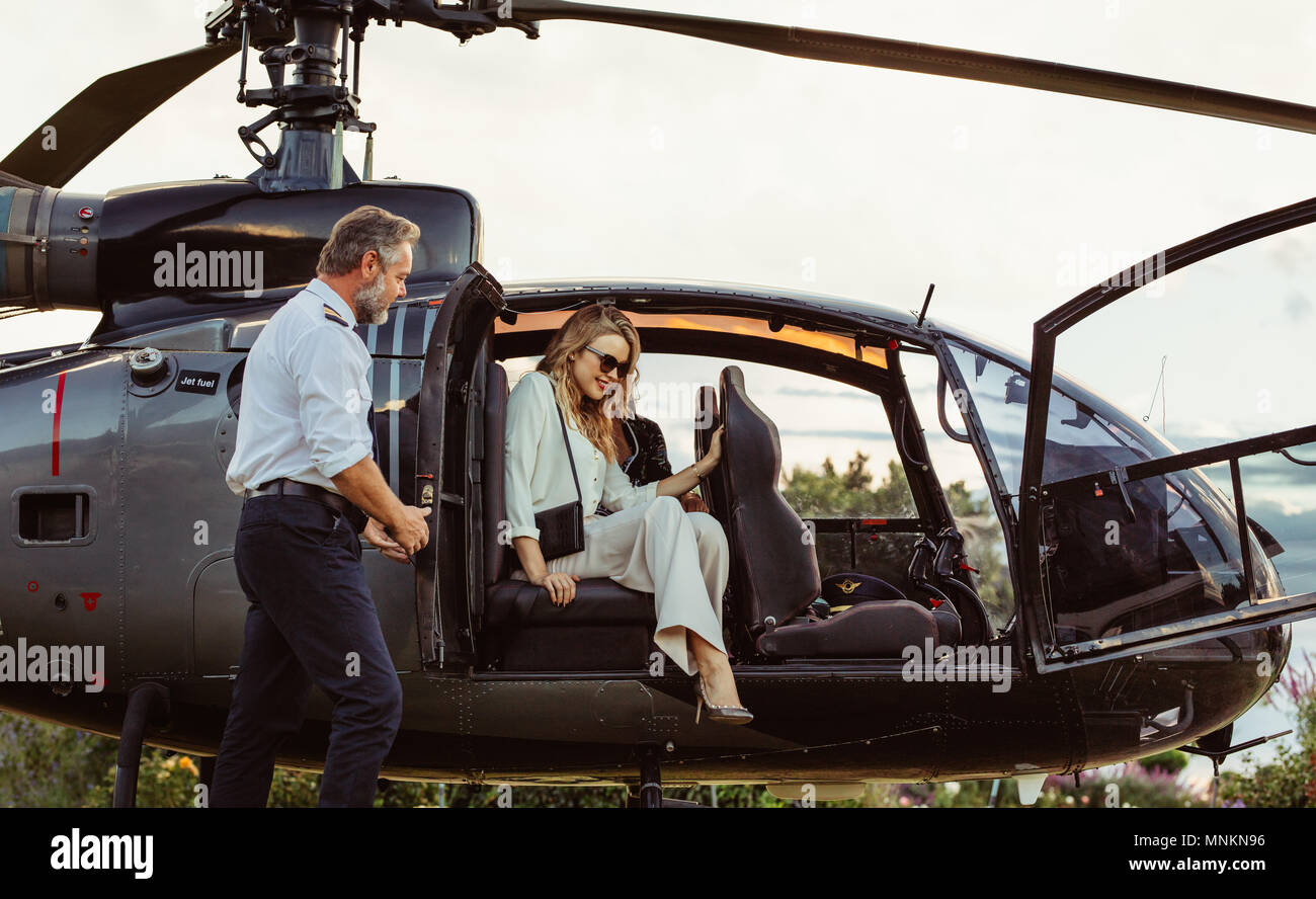 Beautiful young woman getting out of a helicopter with male pilot ...