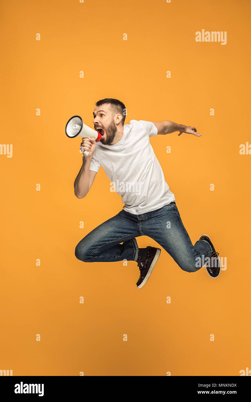 Jumping fan on orange background. The young man as soccer football fan ...