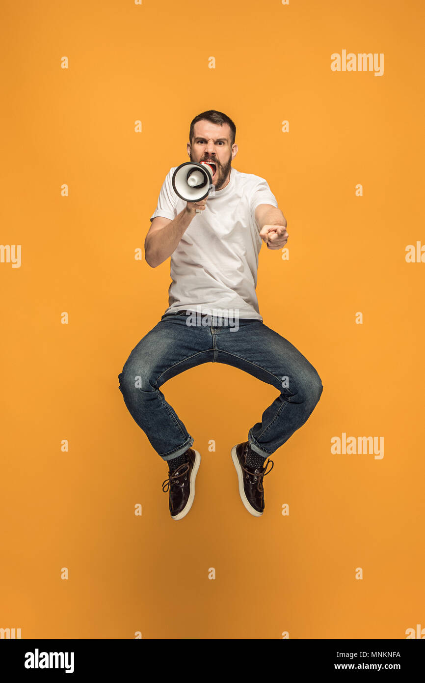 Jumping fan on orange background. The young man as soccer football fan ...