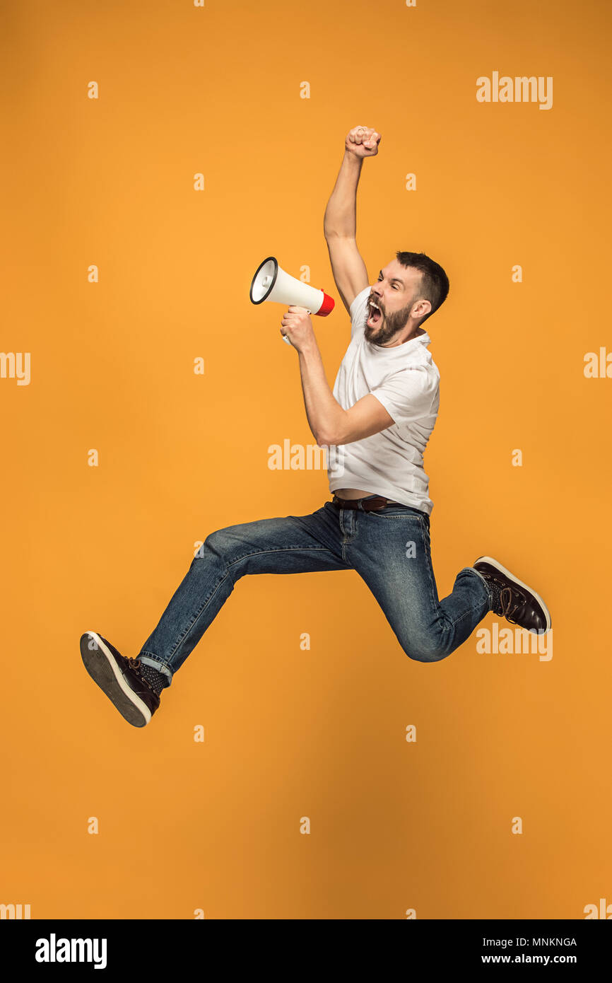 Jumping fan on orange background. The young man as soccer football fan ...