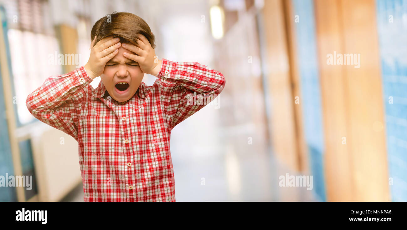 Handsome toddler child with green eyes stressful keeping hands on head ...