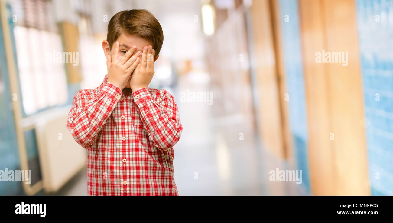 Handsome toddler child with green eyes smiling having shy look peeking ...