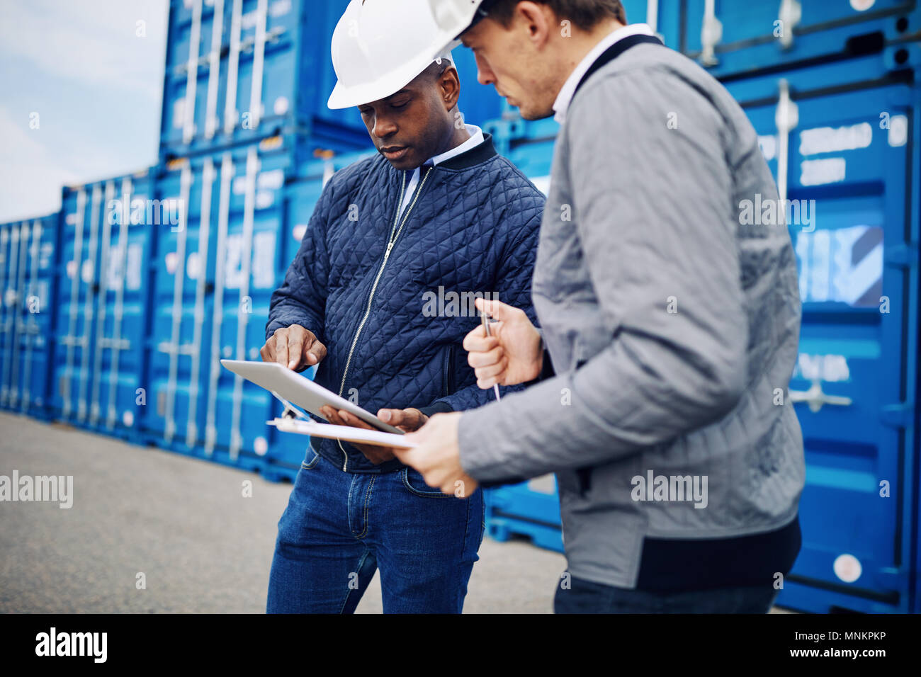 Two engineers tracking inventory using a tablet and a clipboard while ...