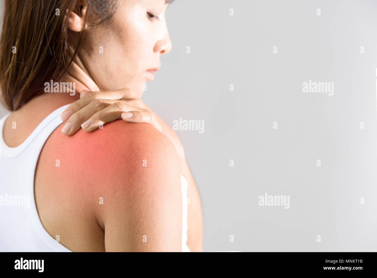 woman holding hand on skin around right shoulder joint with ...