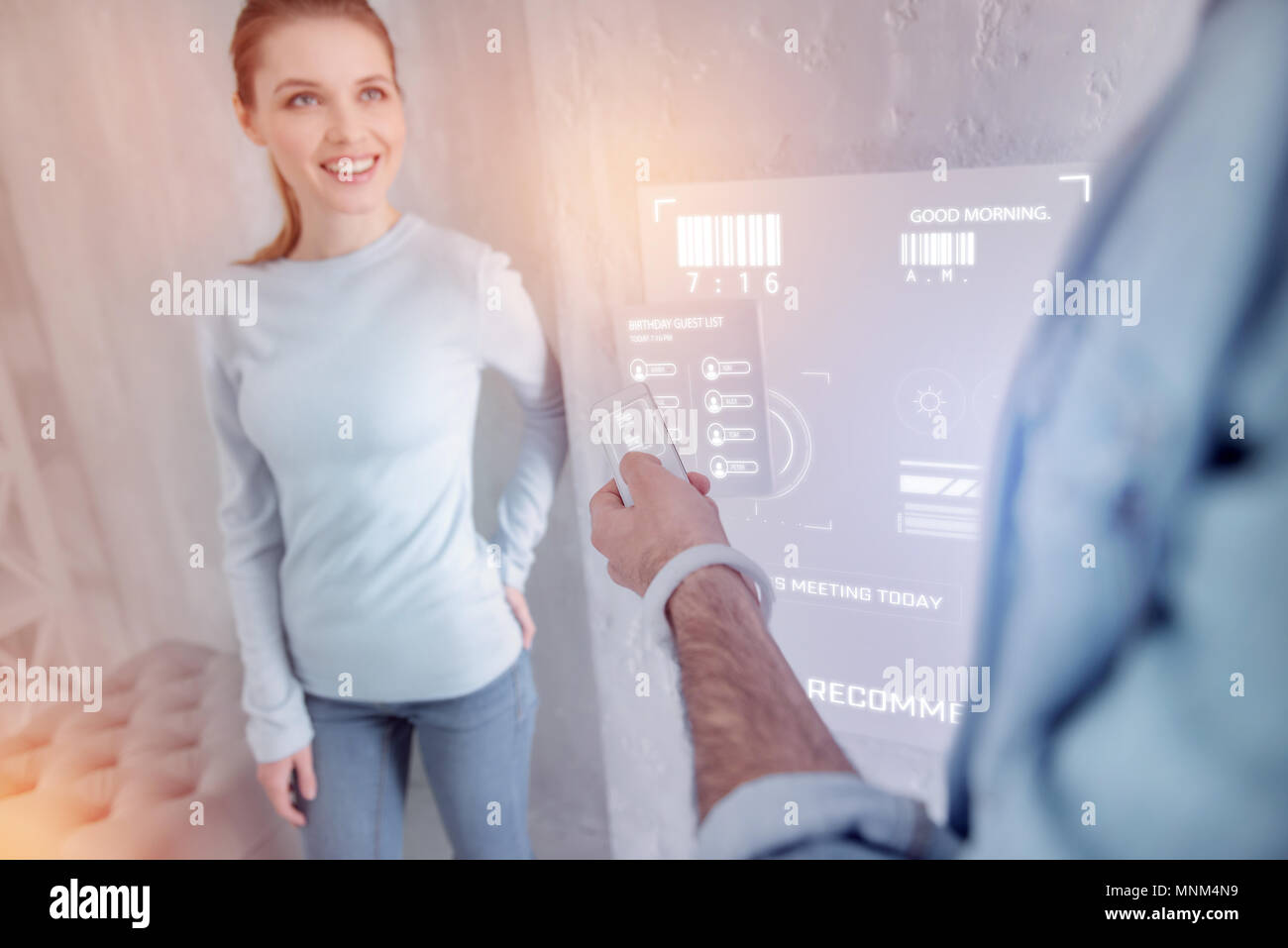 Young man holding a remote control and his cheerful girlfriend smiling ...
