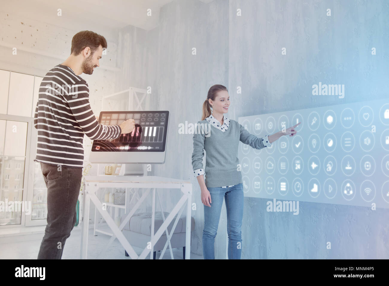 Cheerful programmer working on computer while his coworker standing ...