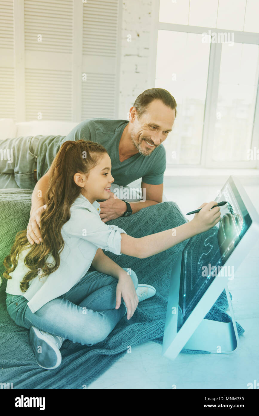 Cheerful girl drawing with a stylus and her kind father smiling Stock ...