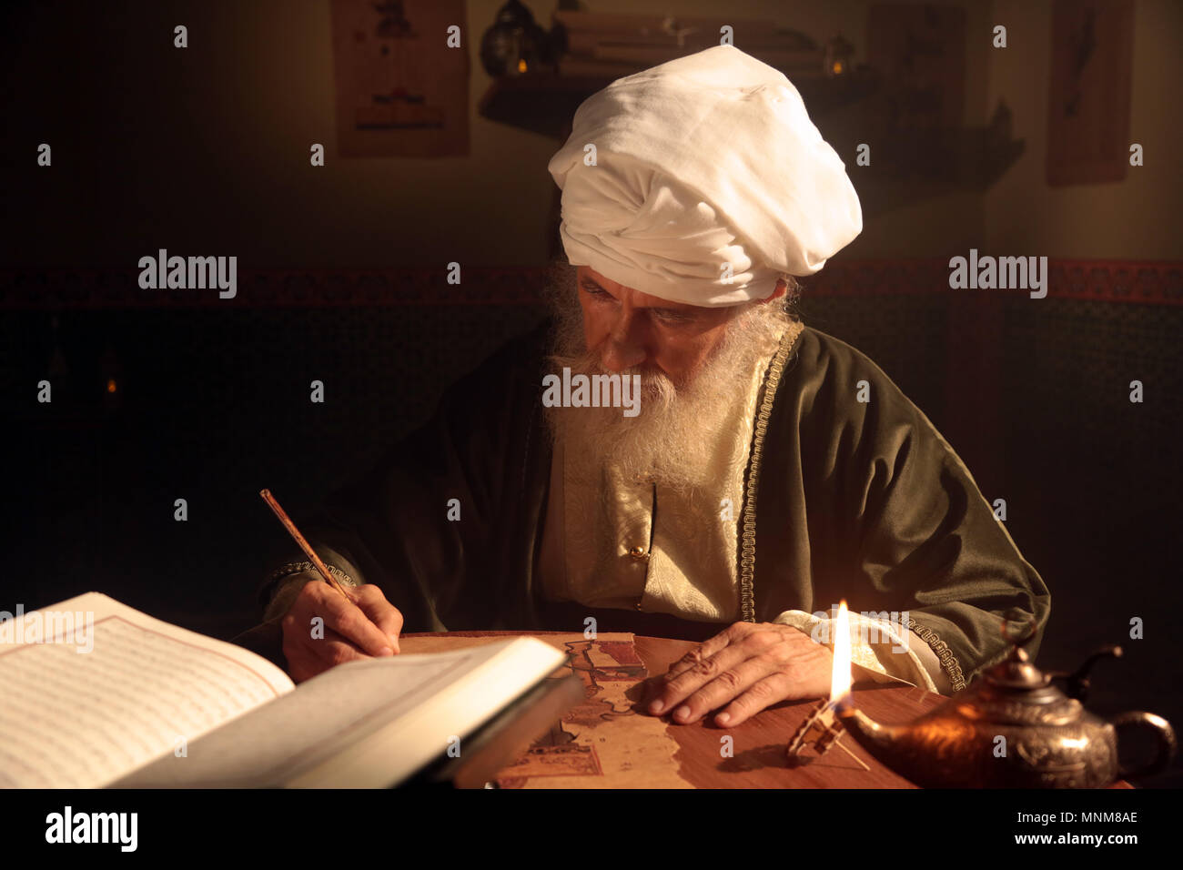An old and historic Islamic scientist is working in his studio writing ...