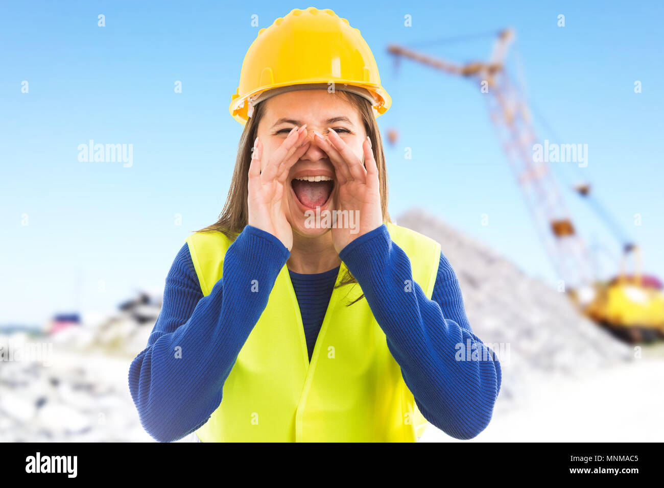 Angry young female engineer or architect shouting with hands on mouth ...