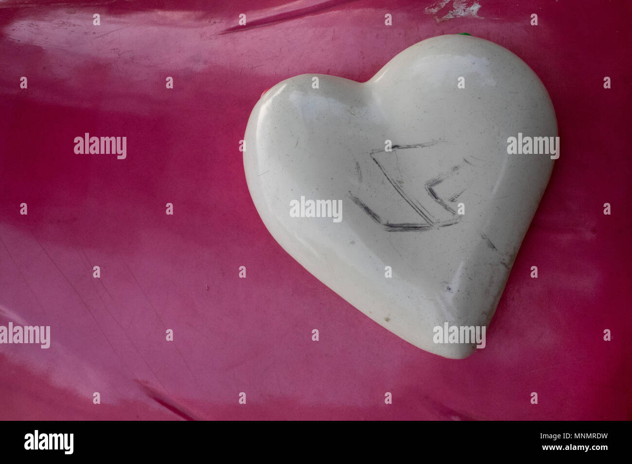 White bulging embossed heart on bright glossy crimson background, a ...