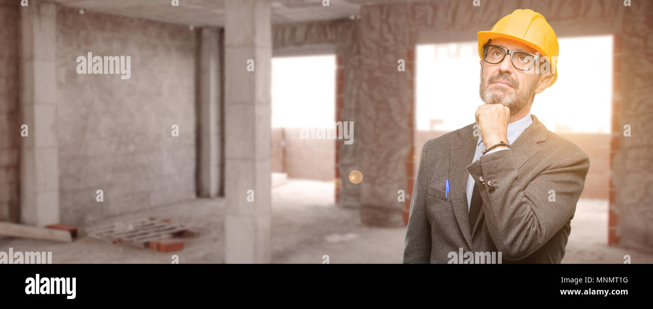 Senior architect or engineer thinking and looking up expressing doubt ...