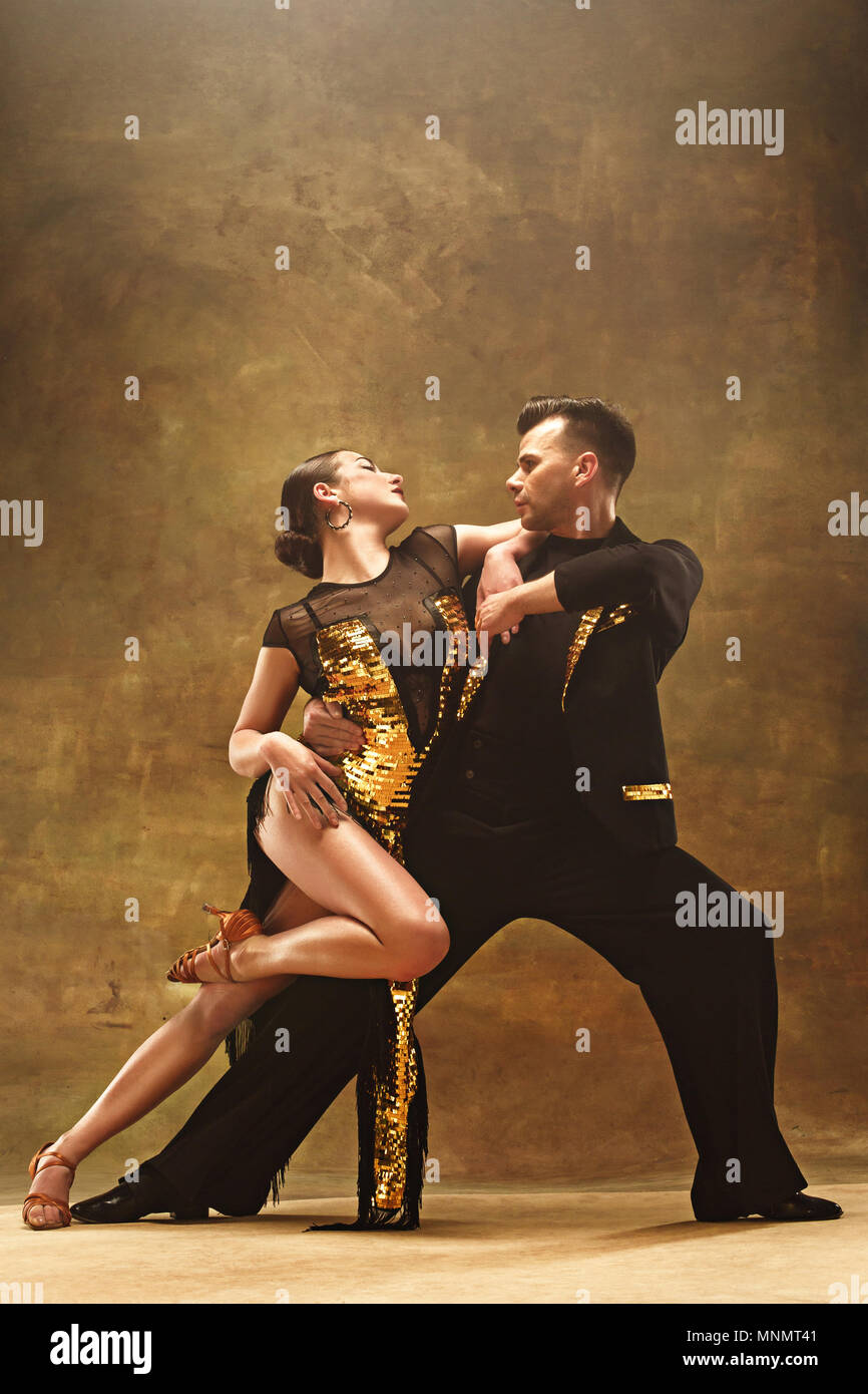 Dance ballroom couple in gold dress dancing on studio background Stock ...