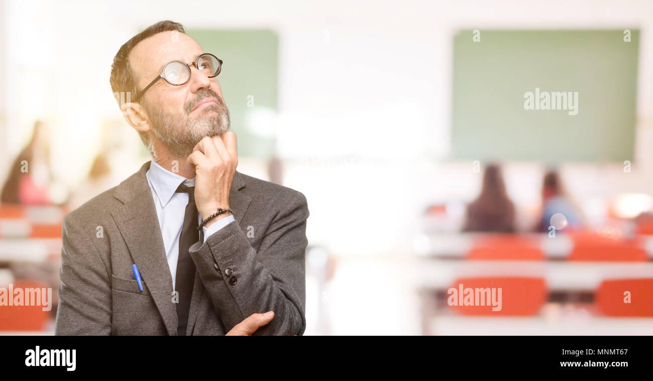 Teacher man using glasses thinking and looking up expressing doubt and ...