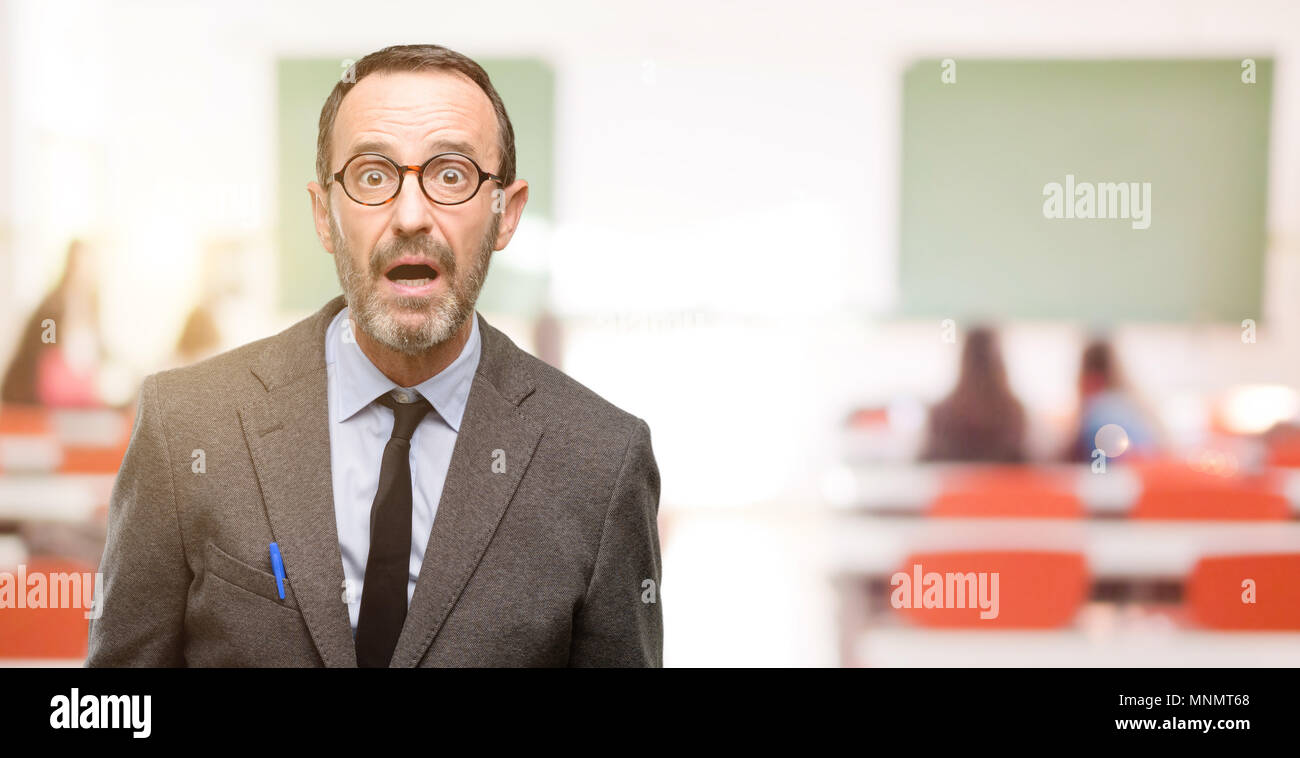 Teacher man using glasses scared in shock, expressing panic and fear at ...