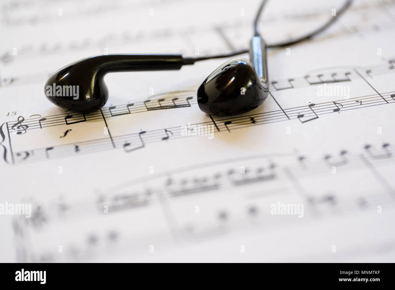 In-ear headphones on sheet music Stock Photo - Alamy