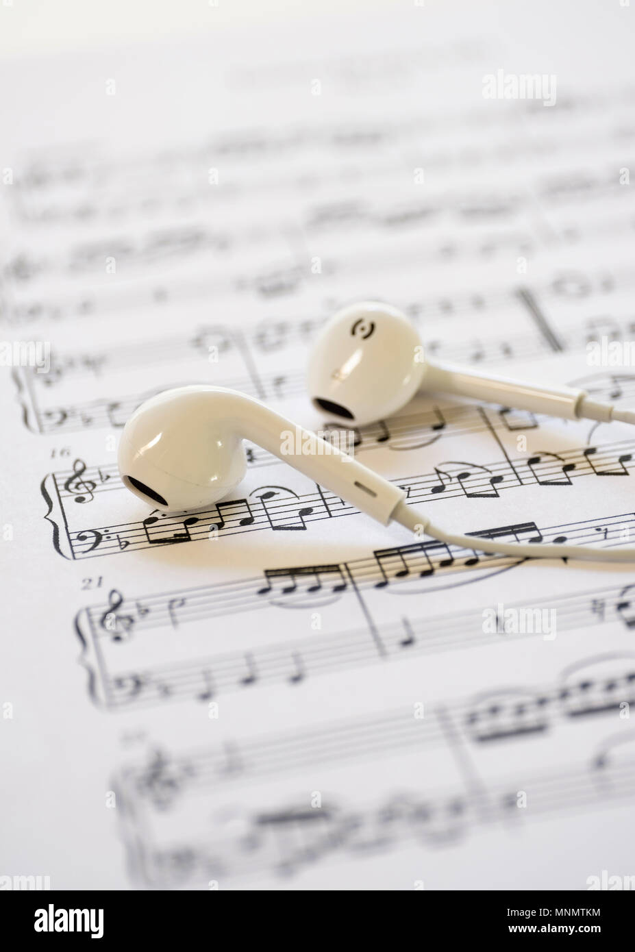 In-ear headphones on sheet music Stock Photo - Alamy