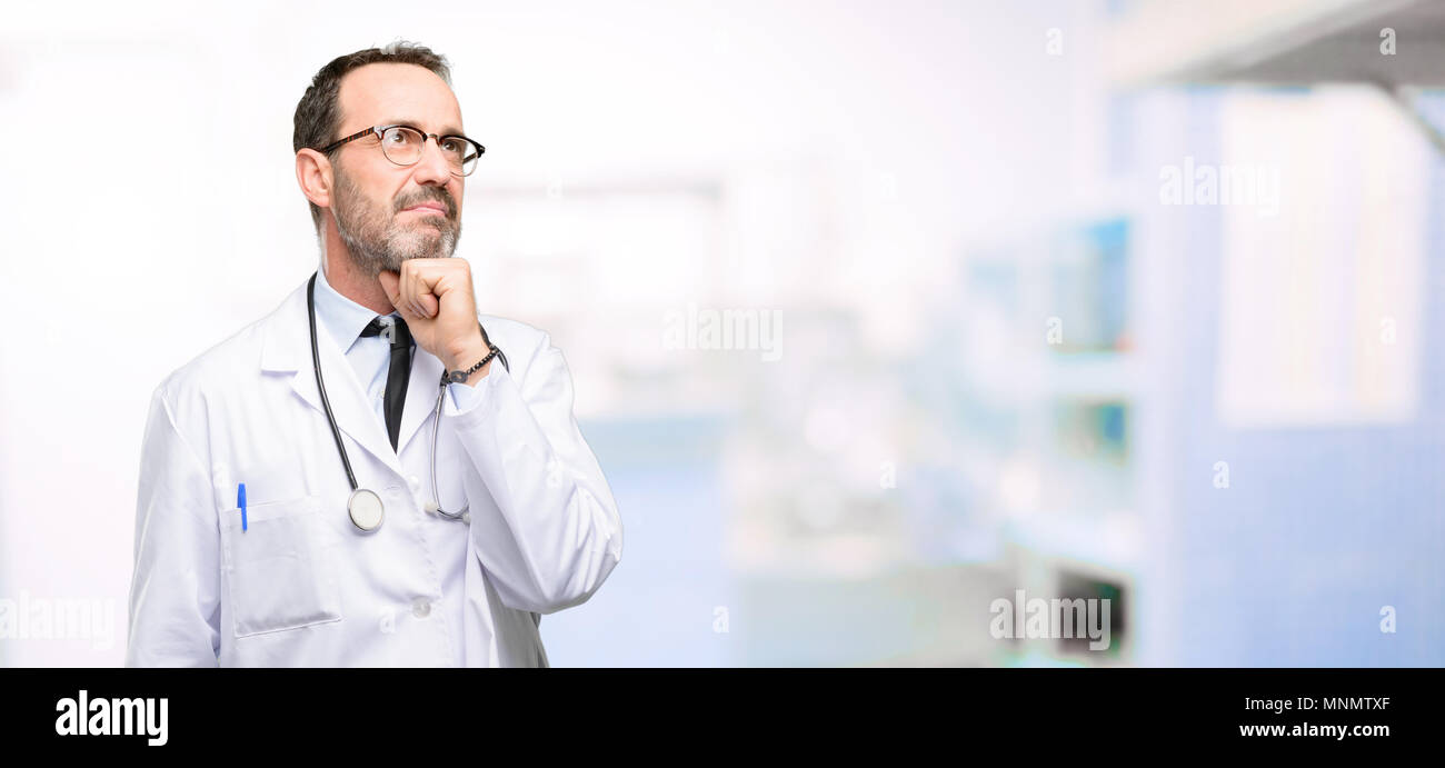 Doctor senior man, medical professional thinking and looking up ...
