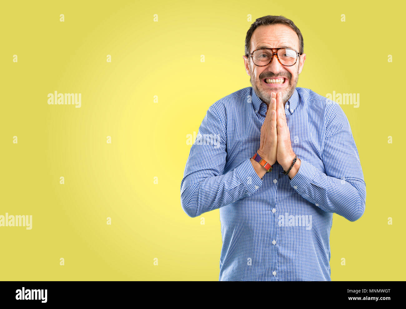 Handsome middle age man with hands together in praying gesture ...