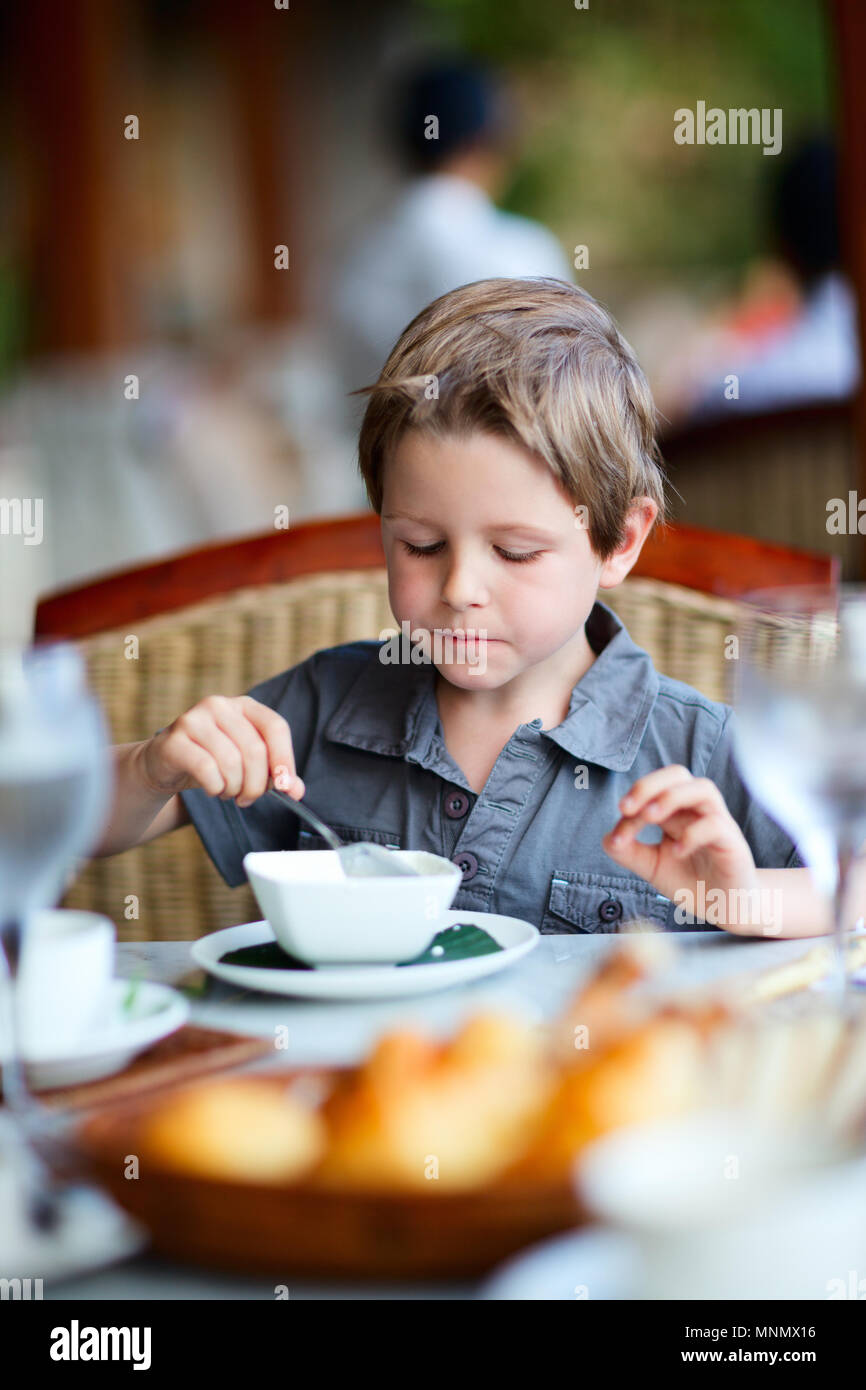Cute boy having delicious breakfast in restaurant Stock Photo - Alamy
