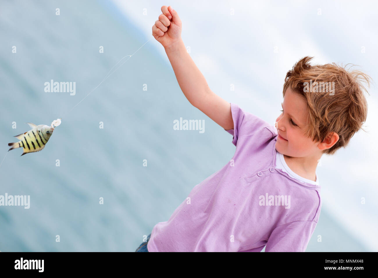 Happy boy holding small fish he just caught Stock Photo - Alamy