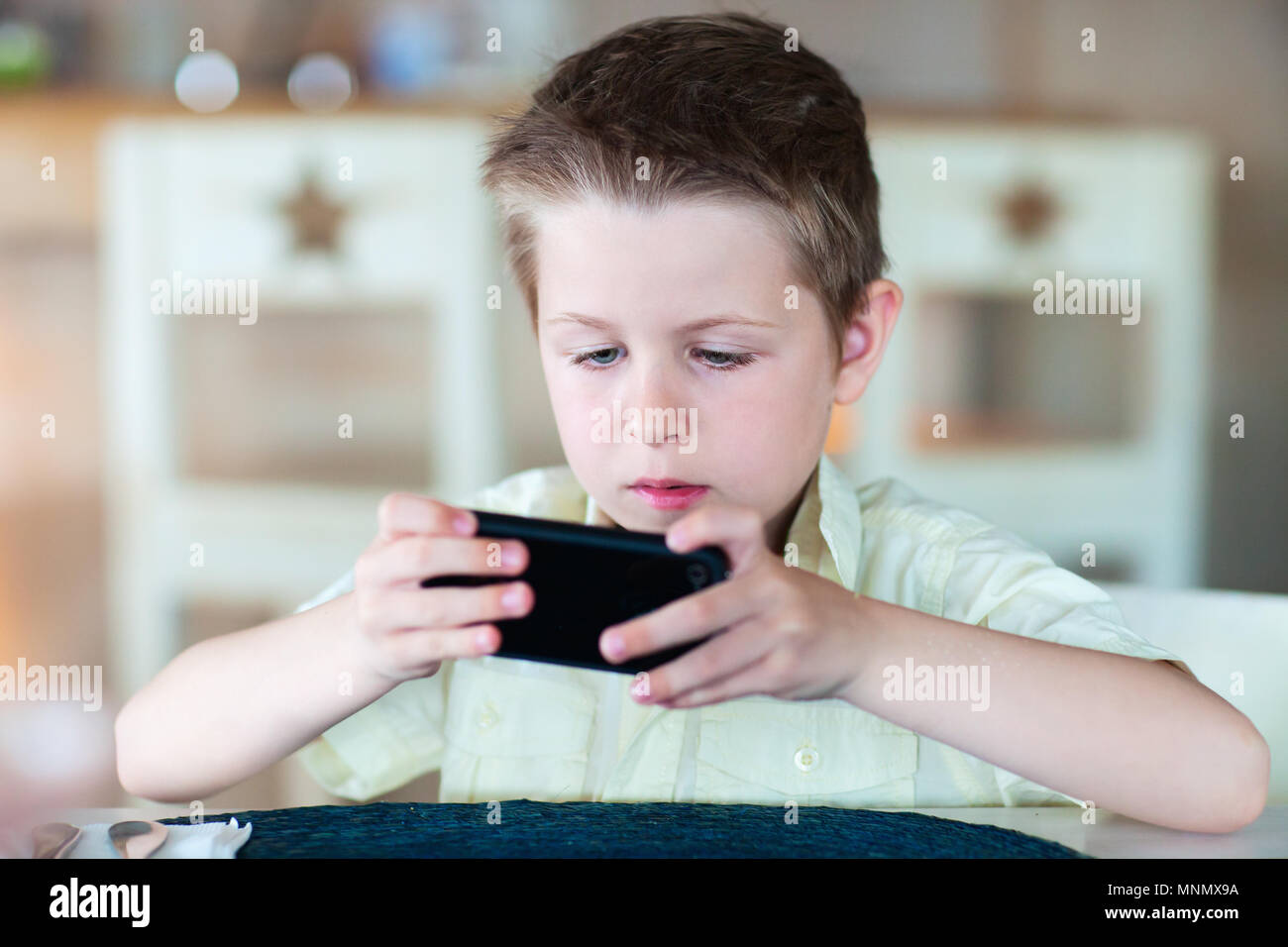 Little boy playing on mobile phone or portable game device Stock Photo ...