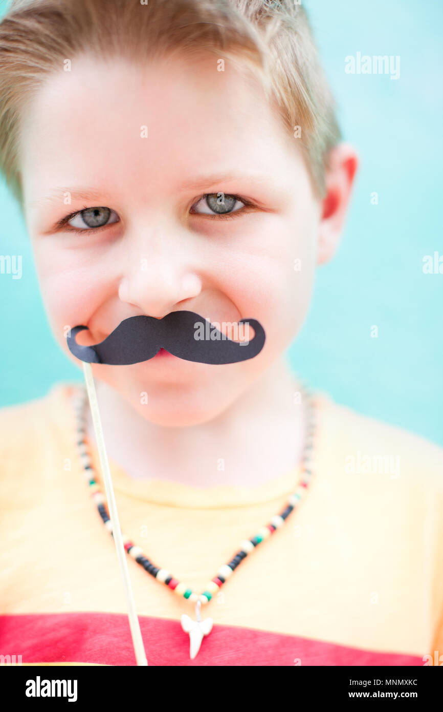 Cute boy holding mustache party accessory Stock Photo - Alamy
