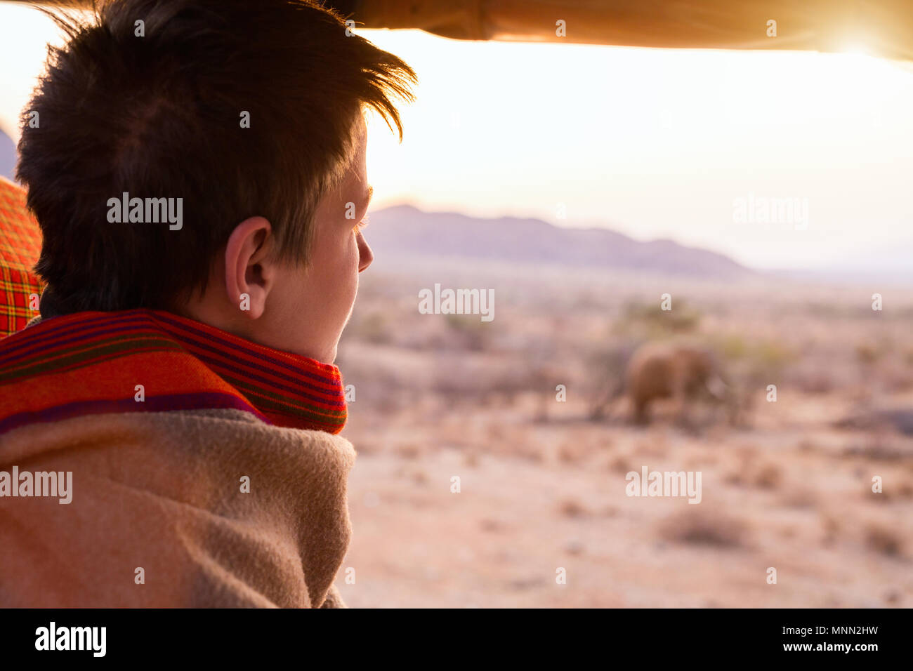 Teenage boy on safari covered with warm blanket outdoors on beautiful ...