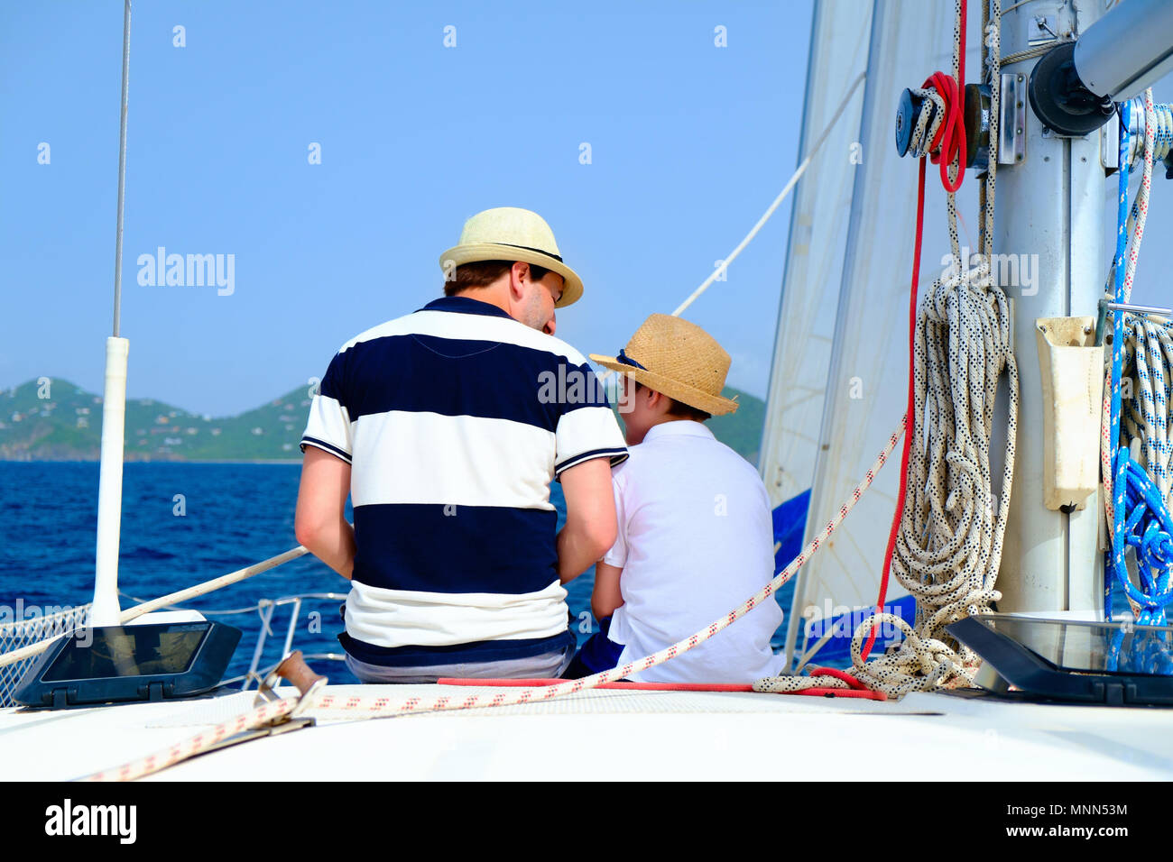 Back view of father and son sailing on a luxury yacht or catamaran boat ...