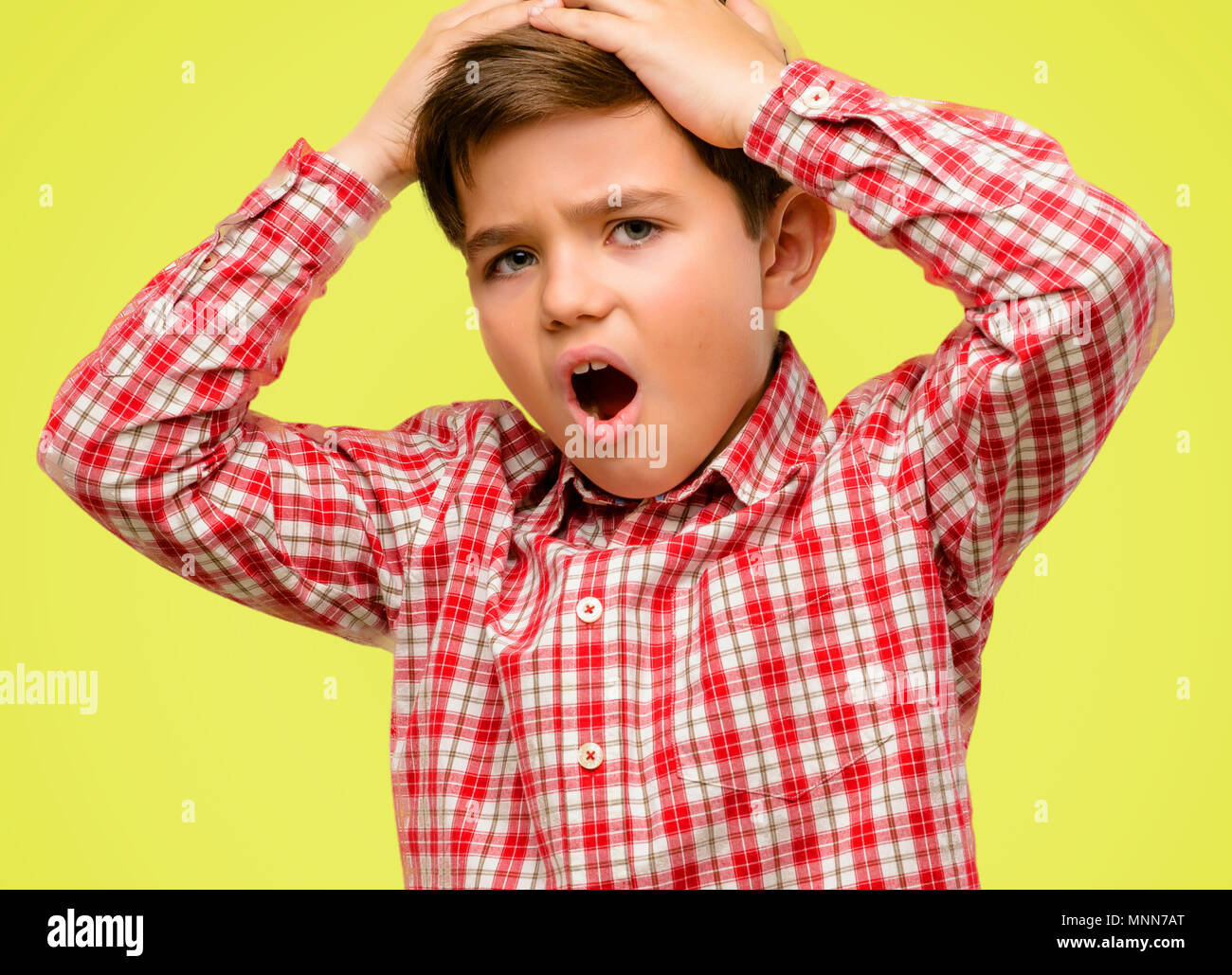 Handsome toddler child with green eyes stressful keeping hands on head ...