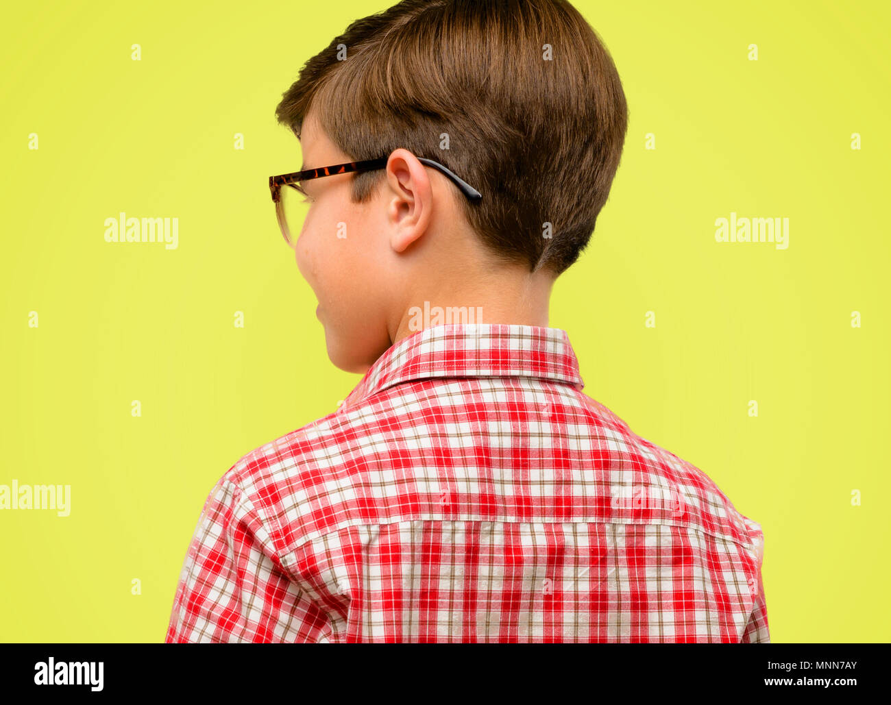 Handsome toddler child with green eyes backside, rear view over yellow ...