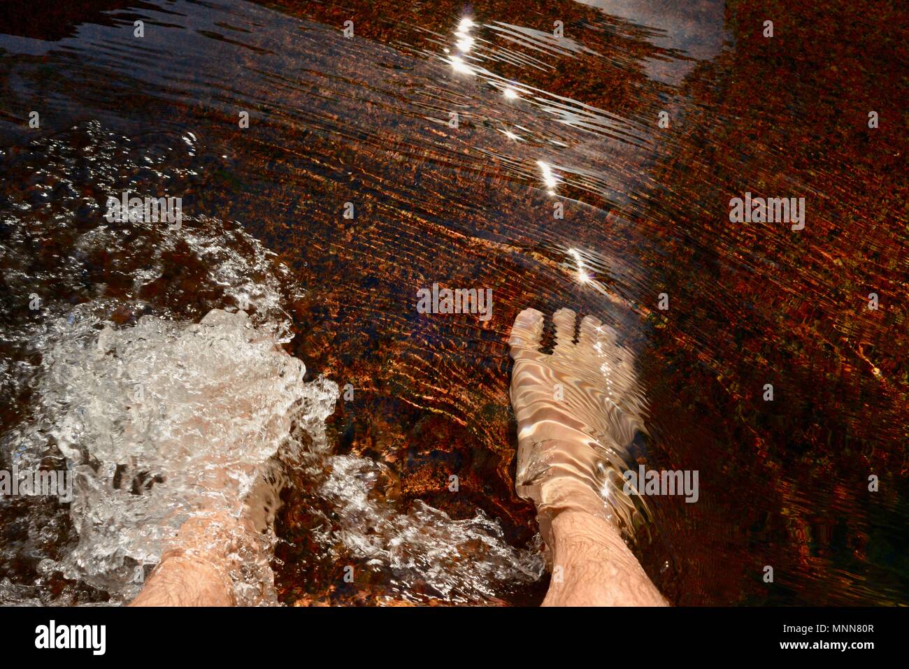 Water flowing through a natural stream around a persons feet hi-res ...