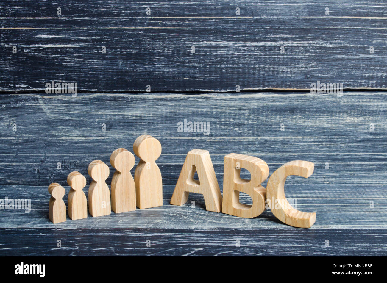 Wooden figures of children stand in a row from small to large near the ...