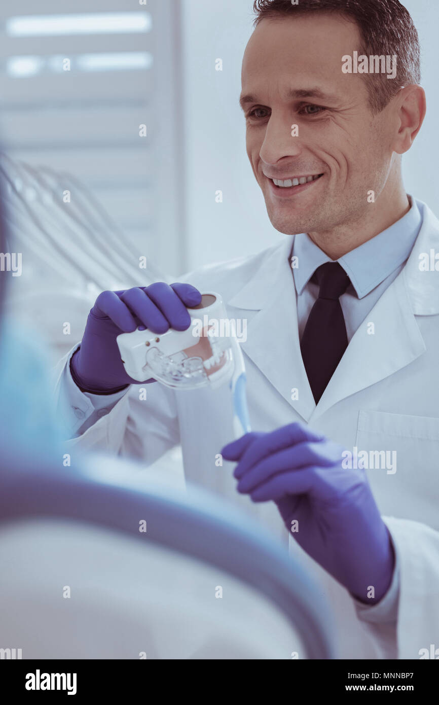 Adorable male dentist calculating dentures size Stock Photo - Alamy