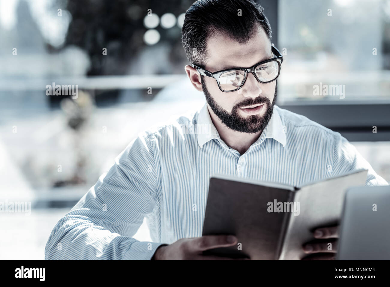 Busy concentrated man sitting and reading his notebook Stock Photo - Alamy